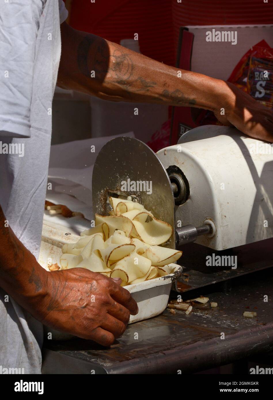 A food booth workers prepares potatoes before cooking them in oil as ...
