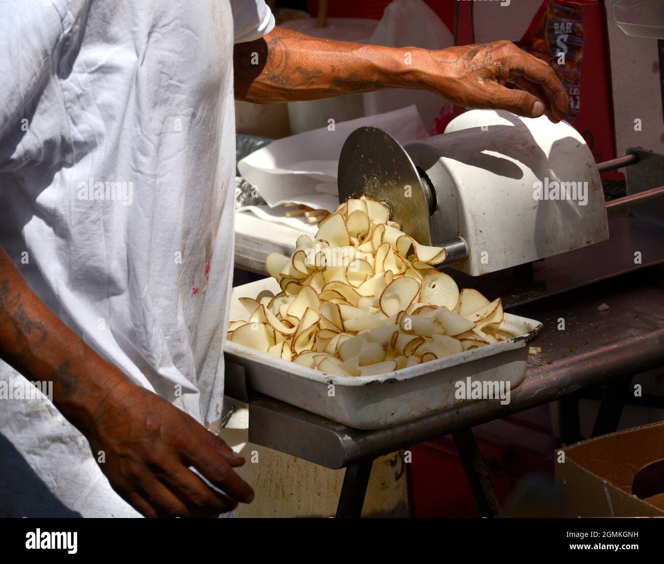 A food booth workers prepares potatoes before cooking them in oil as ...