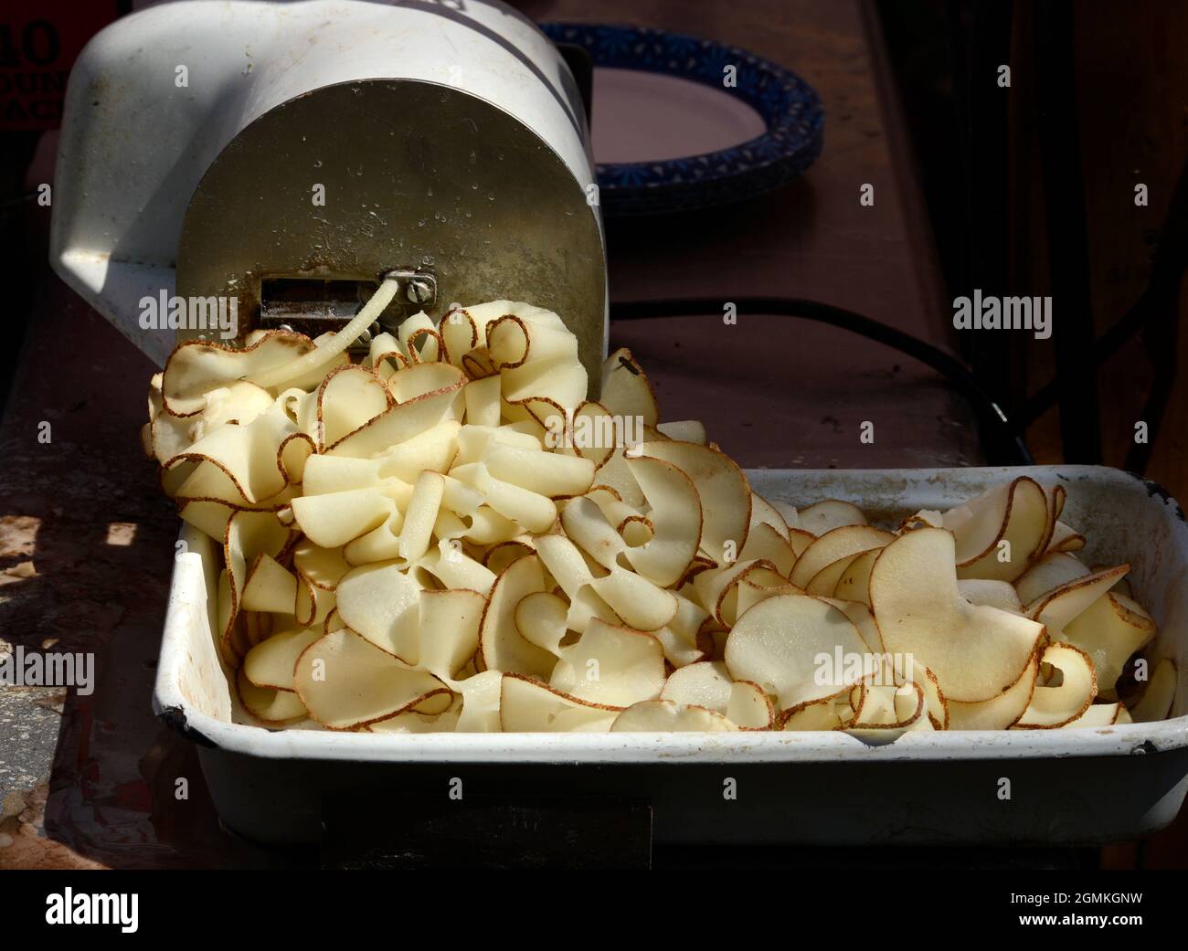 A food booth workers prepares potatoes before cooking them in oil as ...