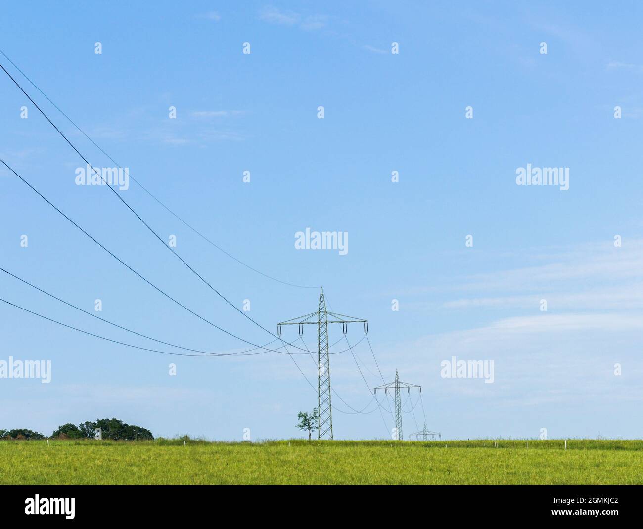 A row of transmission towers with electricity wires in a large, green ...