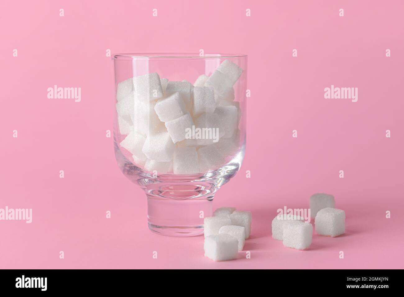 Glass with sweet sugar on color background Stock Photo - Alamy