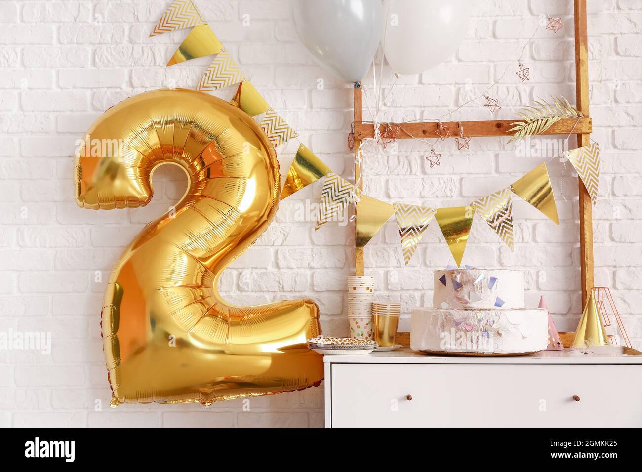Chest of drawers with birthday cake and balloons near brick wall Stock ...