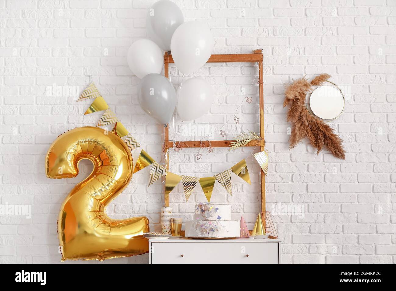 Chest of drawers with birthday cake and balloons near brick wall Stock ...