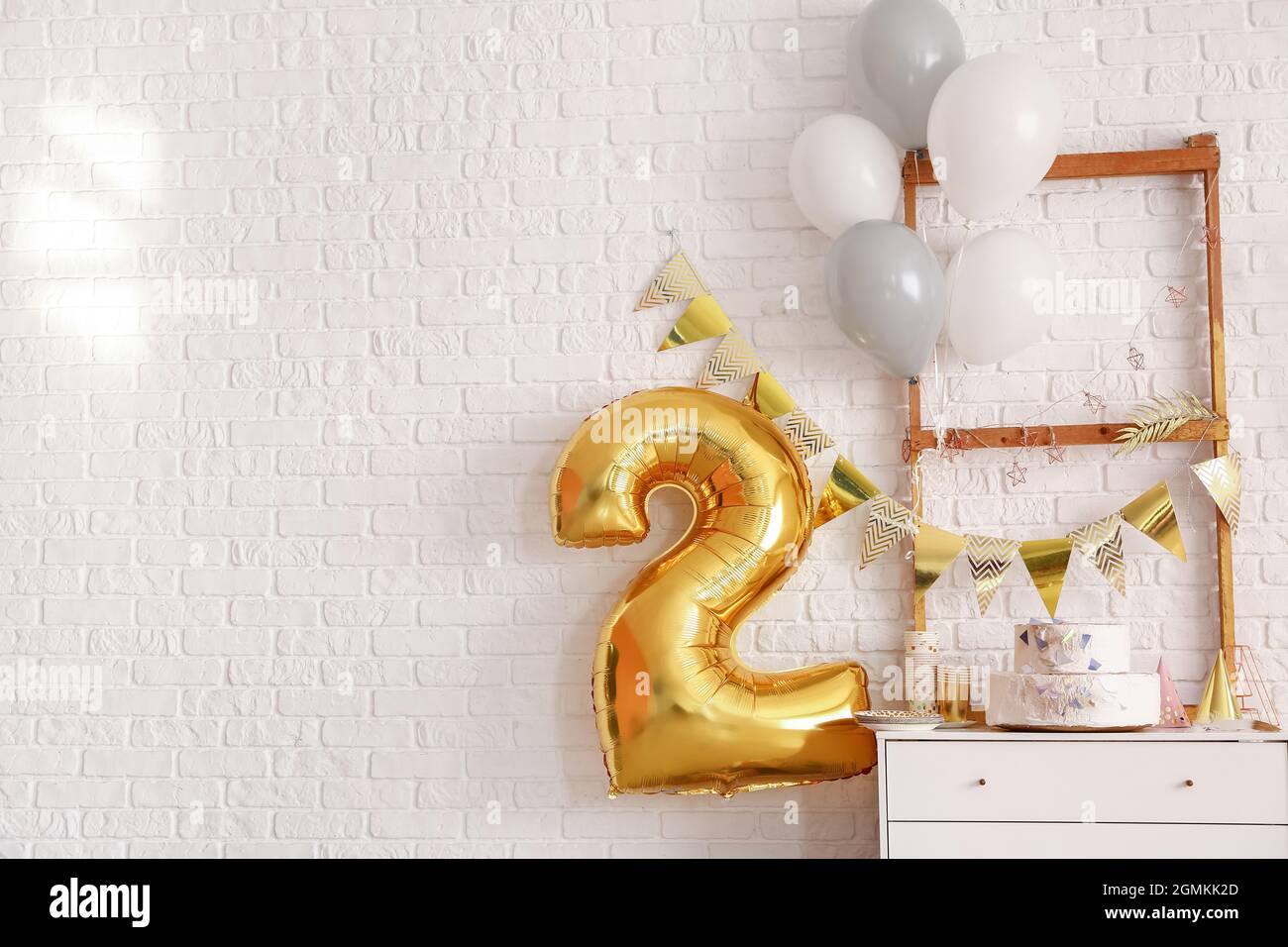 Chest of drawers with birthday cake and balloons near brick wall Stock ...
