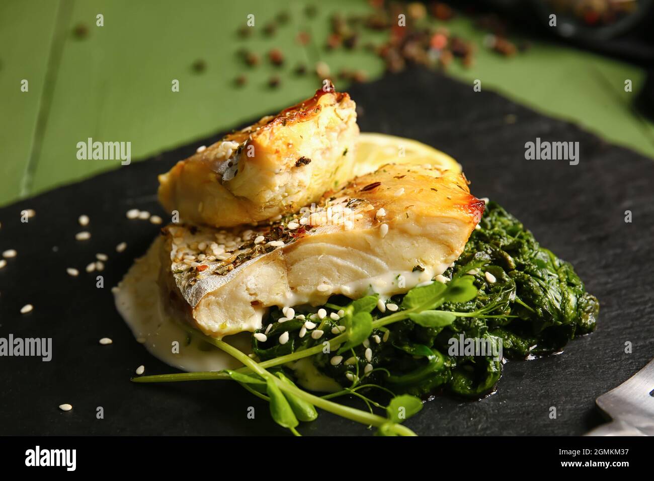 Board with tasty baked cod fillet, pesto sauce and greens on color ...