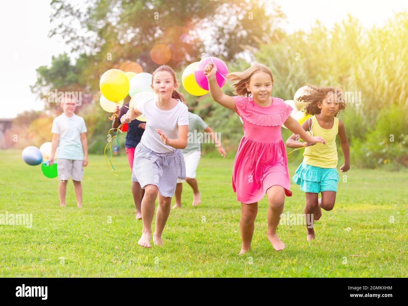 Kids with balloons running through field Stock Photo - Alamy