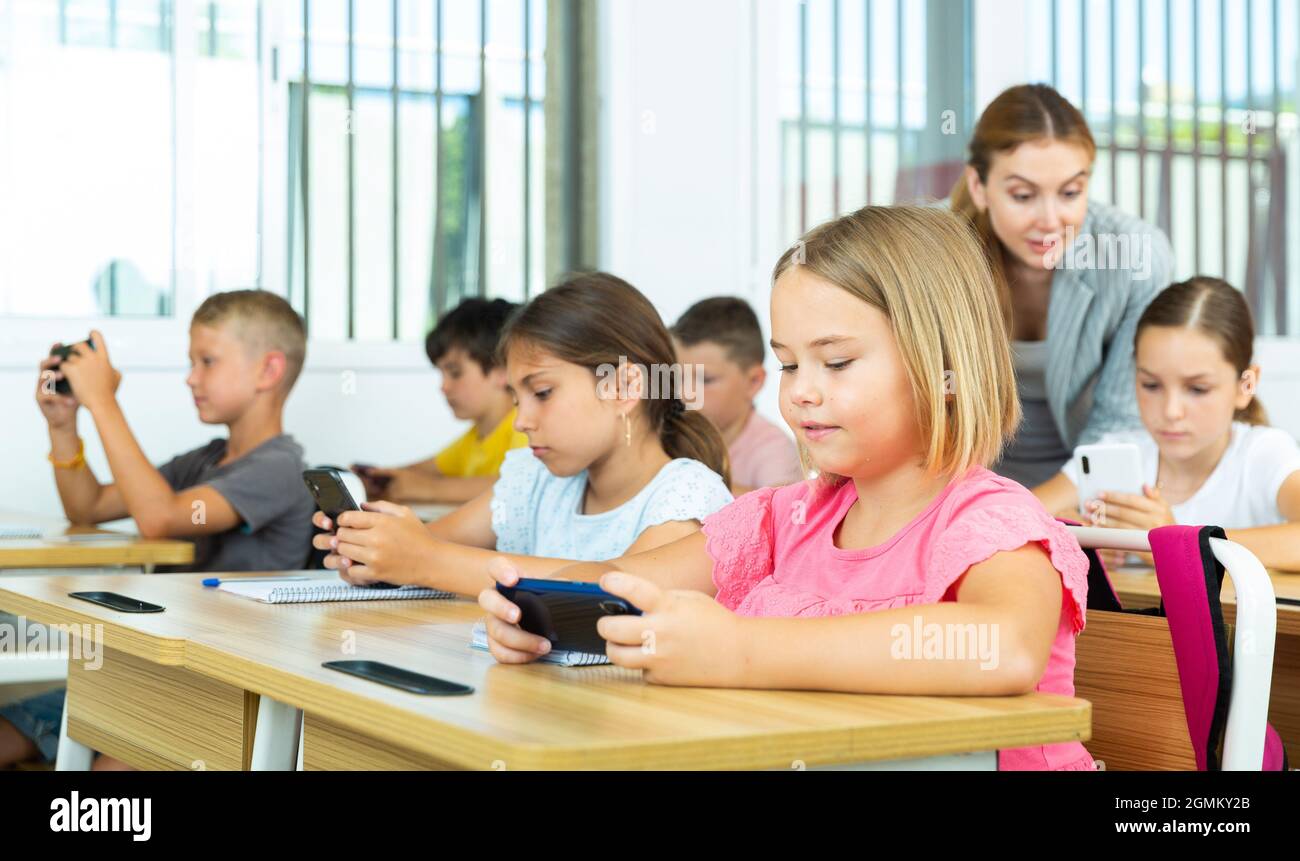 Kids using smartphones during lesson Stock Photo - Alamy