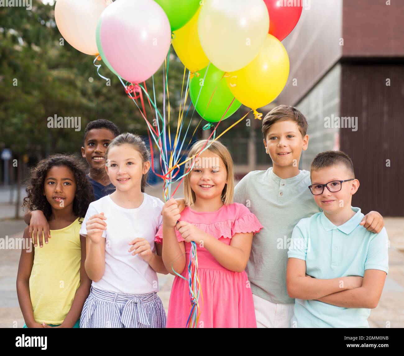 Cheerful happy tween children with colorful balloons on city street ...