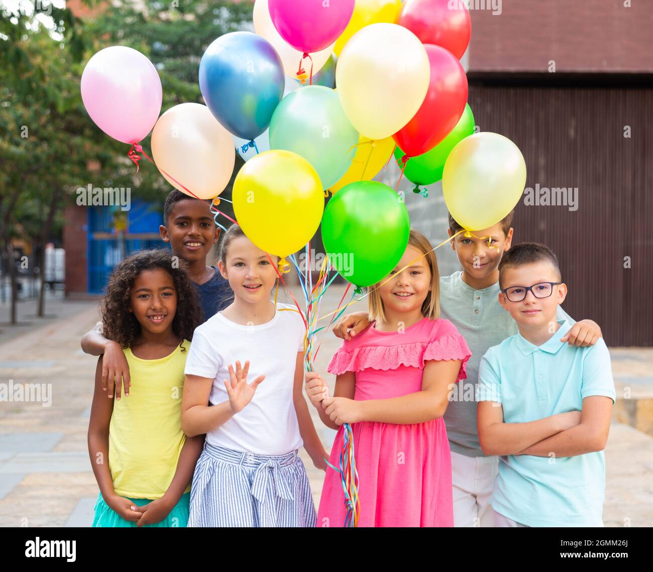 Cheerful happy tween children with colorful balloons on city street ...