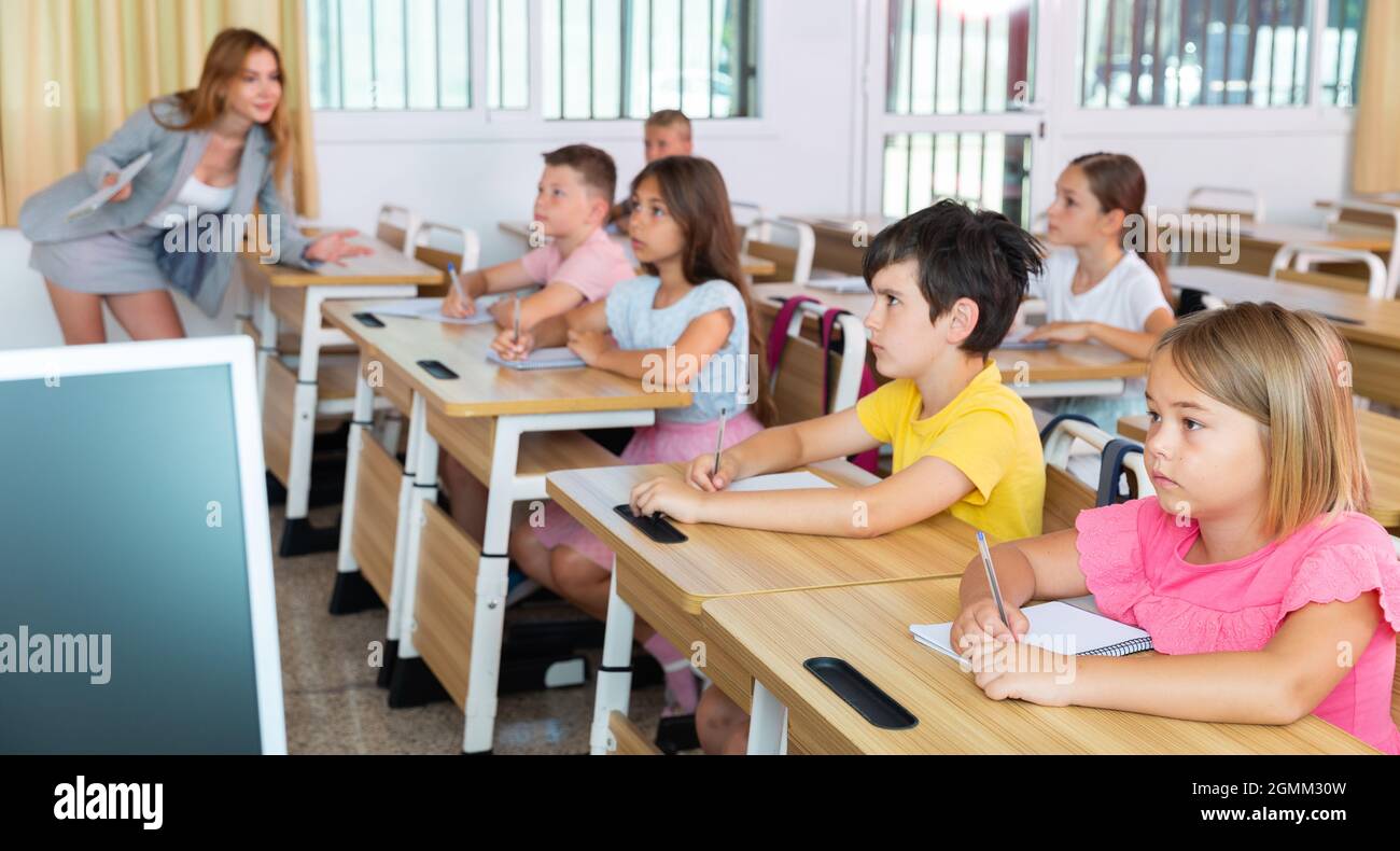 Group of school kids and teacher during lesson in classroom Stock Photo ...