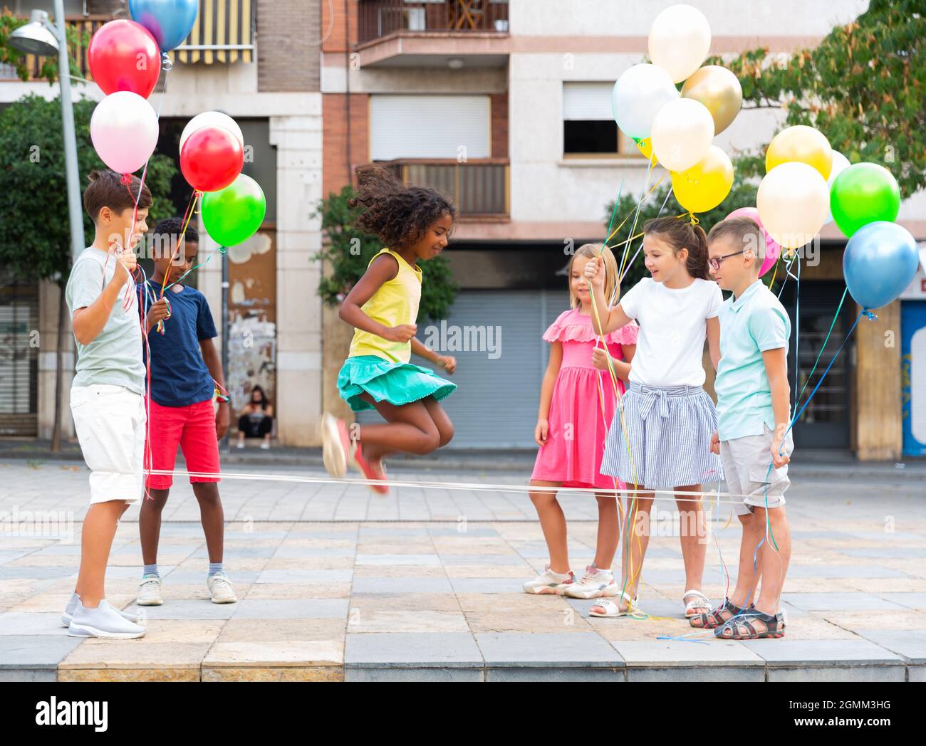 Kids playing with Chinese jumping rope outdoors Stock Photo - Alamy