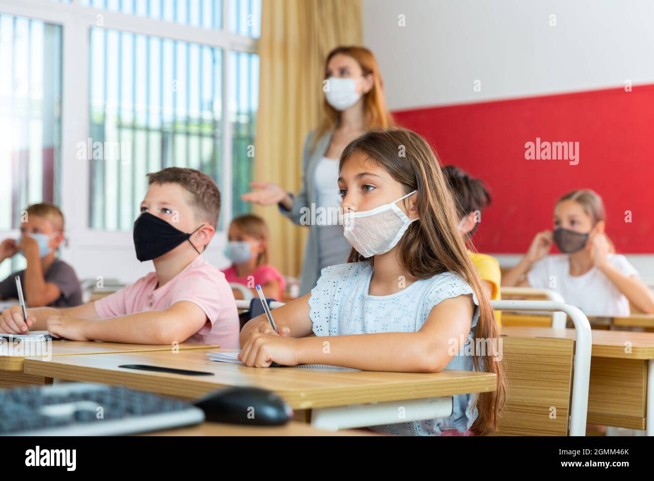 Kids in masks studying in classroom Stock Photo - Alamy
