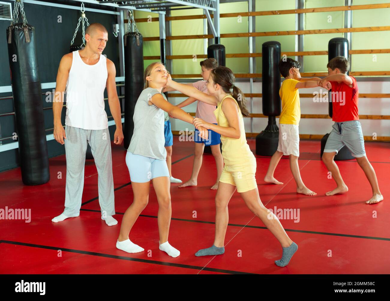 Preteen children practicing in pair self-defence movements with male ...