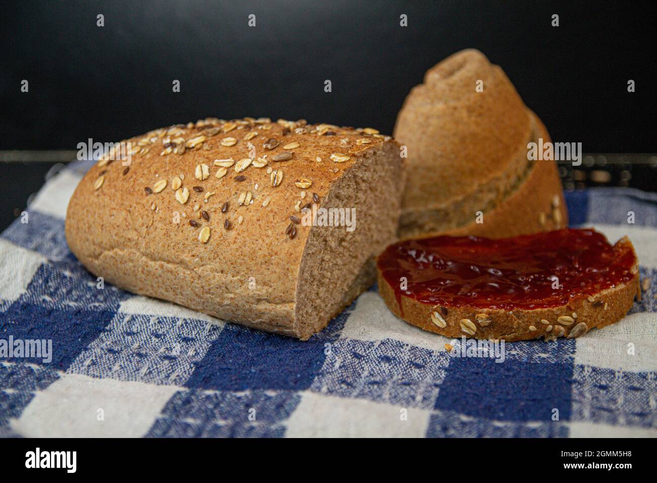 Closeup shot of sliced bread with strawberry jam on a checkered cloth ...