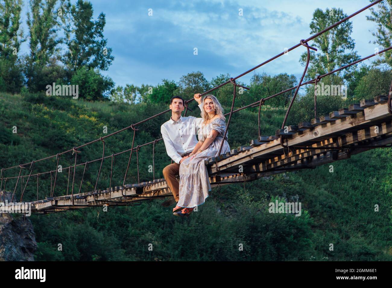 Beautiful young romantic couple sitting and hugging on the suspension ...