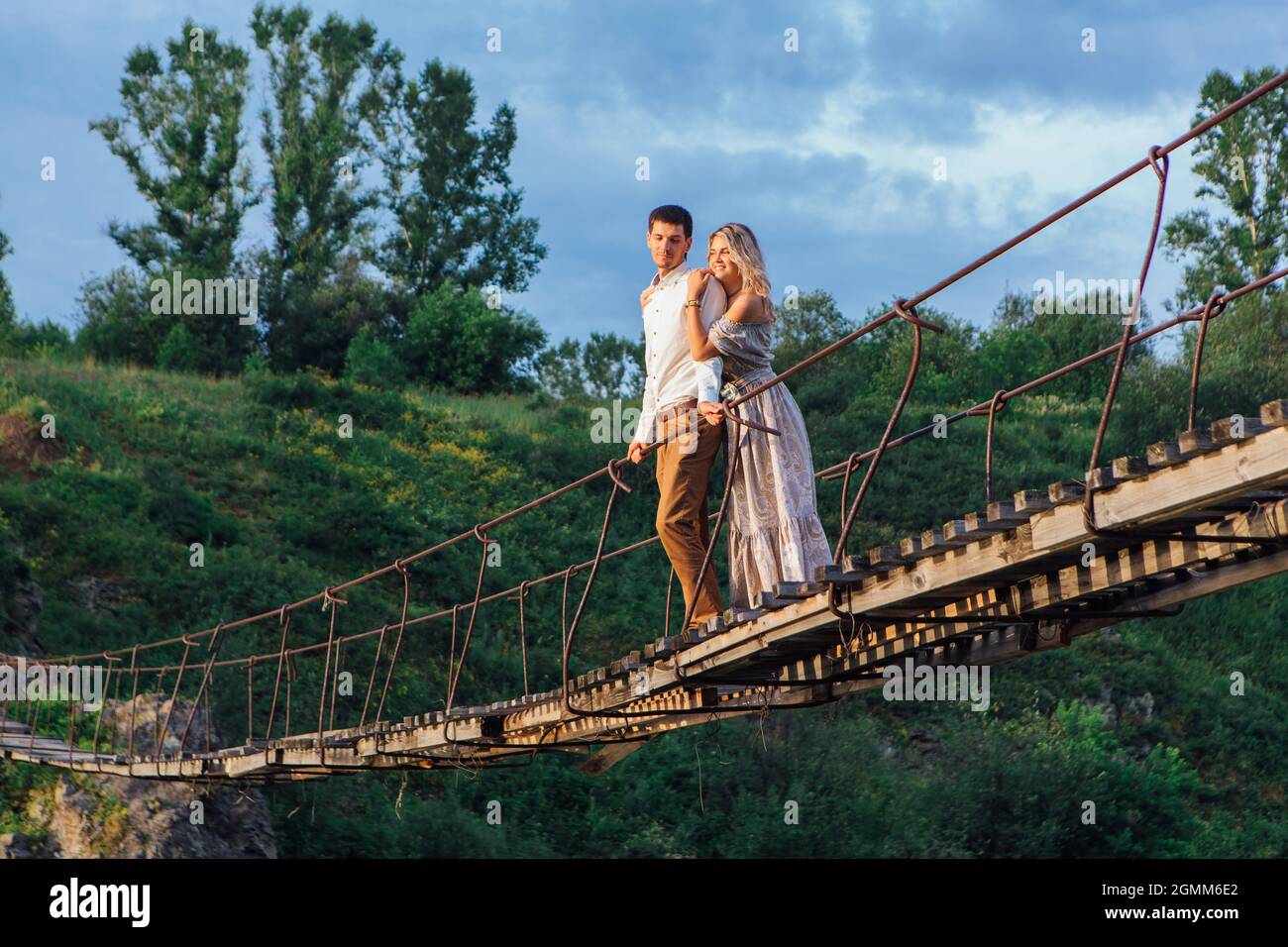 Beautiful young romantic couple standing and hugging on the suspension ...