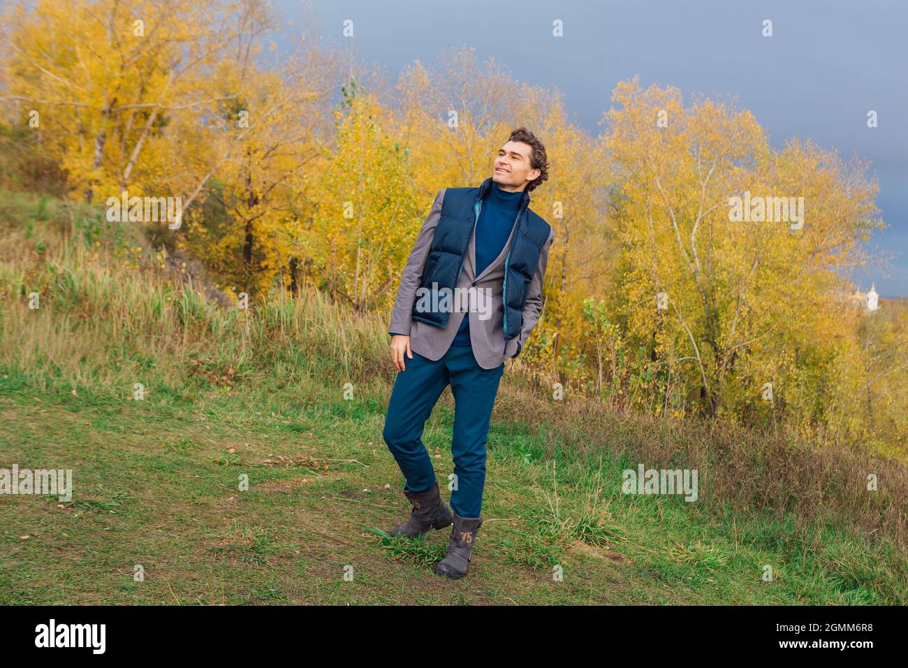 Tall handsome man walking outdoor in yellow autumn forest on the hill ...