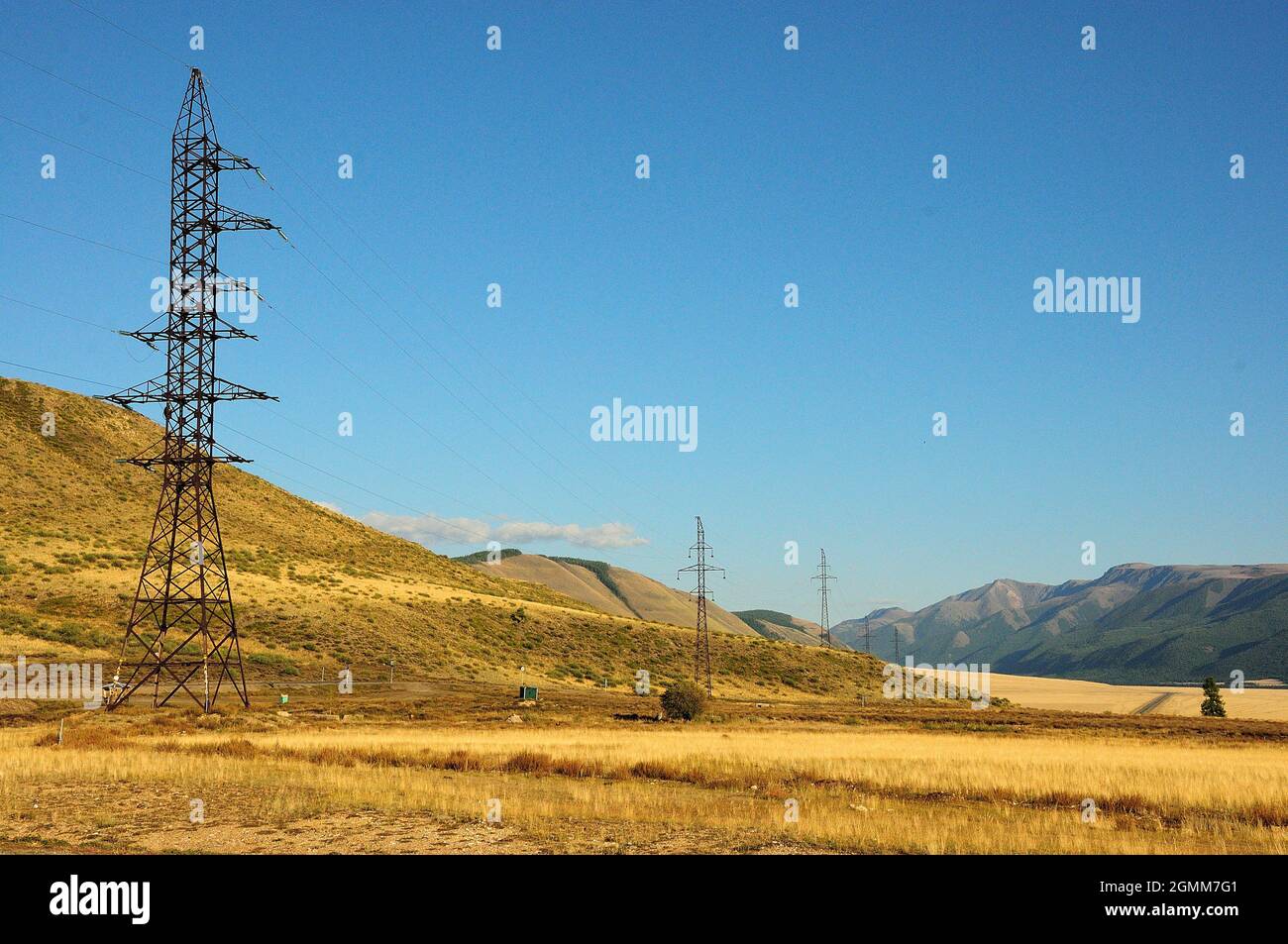 Tall metal poles of power lines run through the hills and steppe in ...