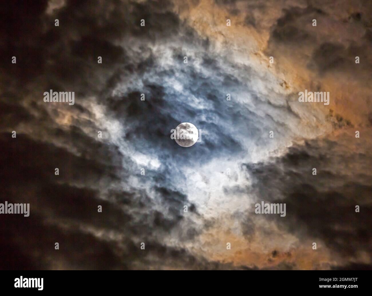 The glow of a full moon dramatically lights clouds in a night sky Stock ...