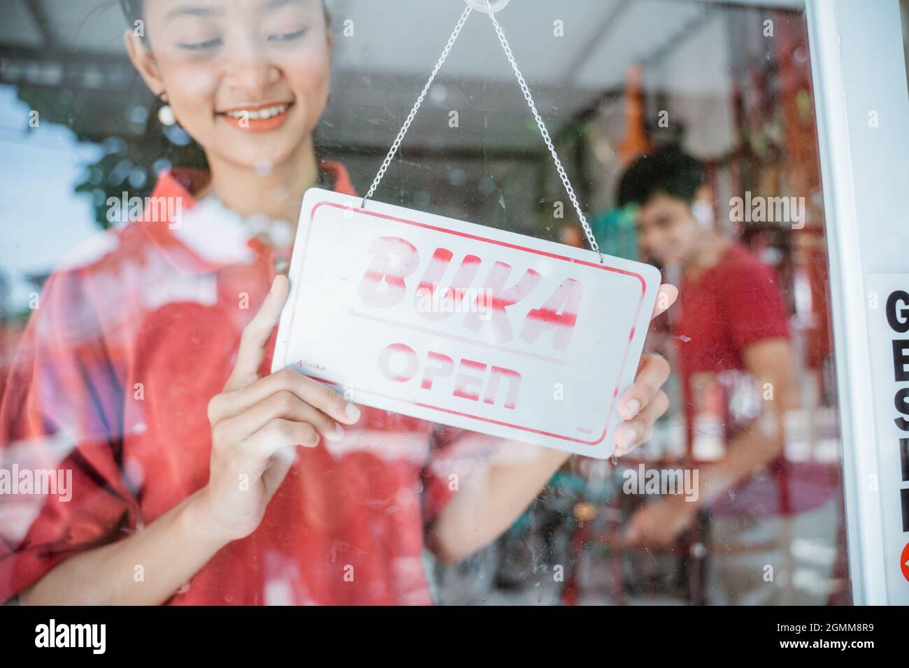 a girl wearing a red t-shirt with an open sign on the front glass door ...