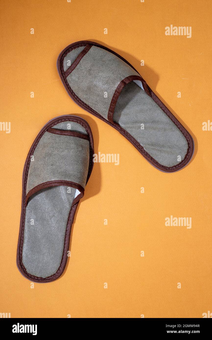 Gray one-off slippers for hotel on a color background Stock Photo - Alamy