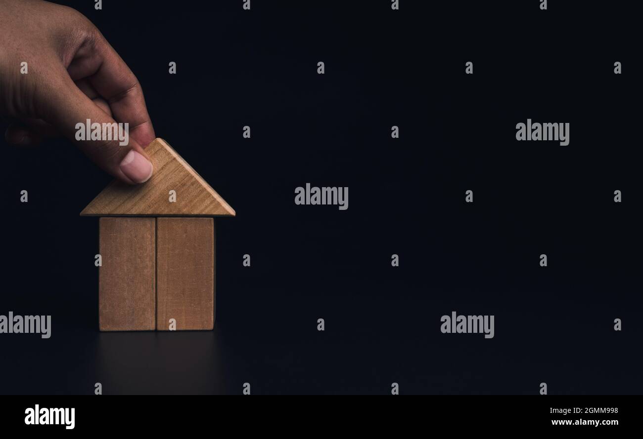 Hand building house with wooden blocks, laying of the roof on dark ...