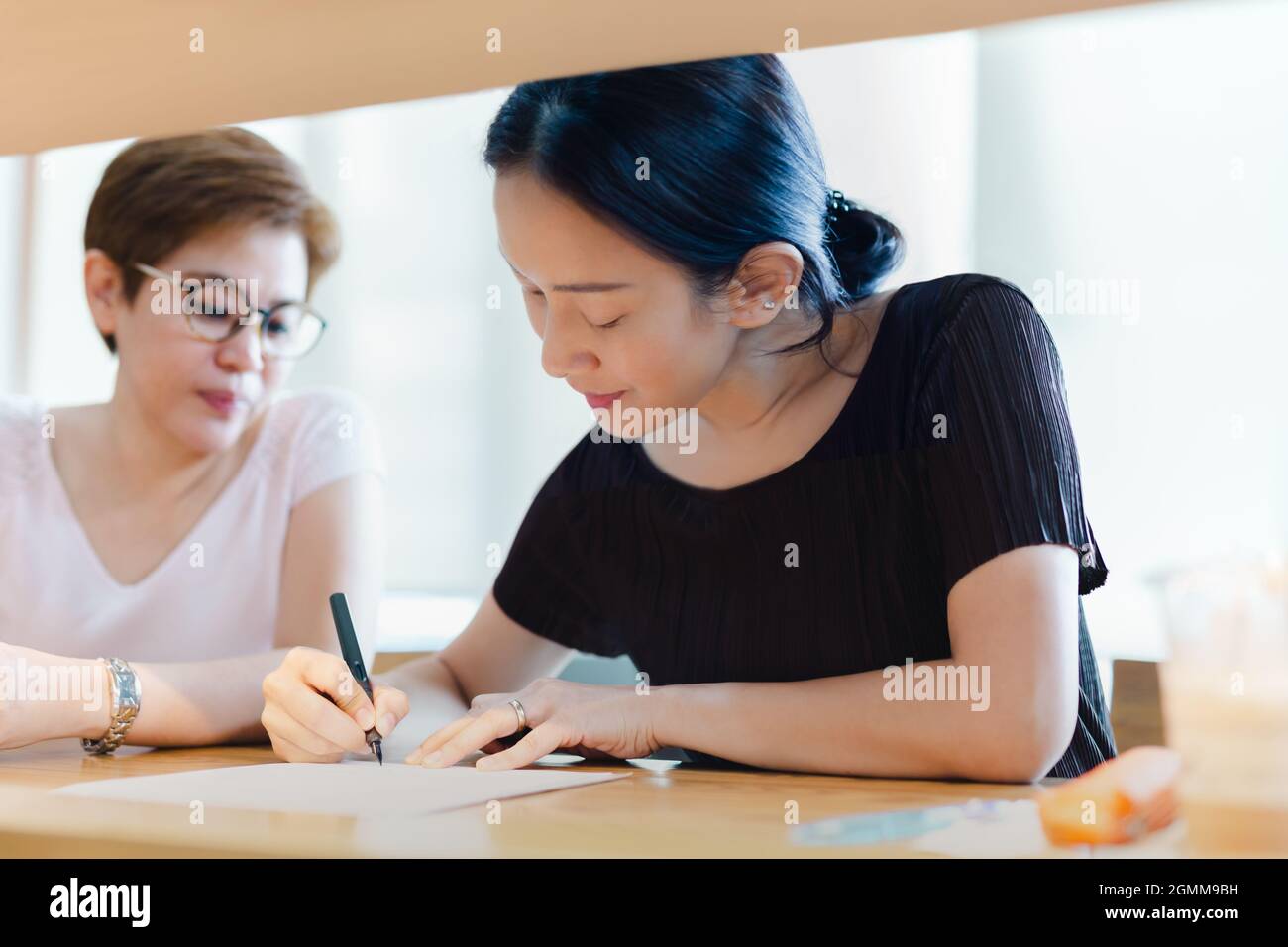 Two business woman signing contract agreement during meeting in cafe ...