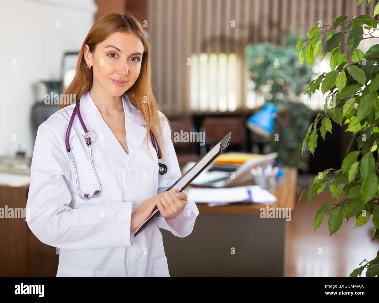 Female doctor standing in hall and smiling Stock Photo - Alamy