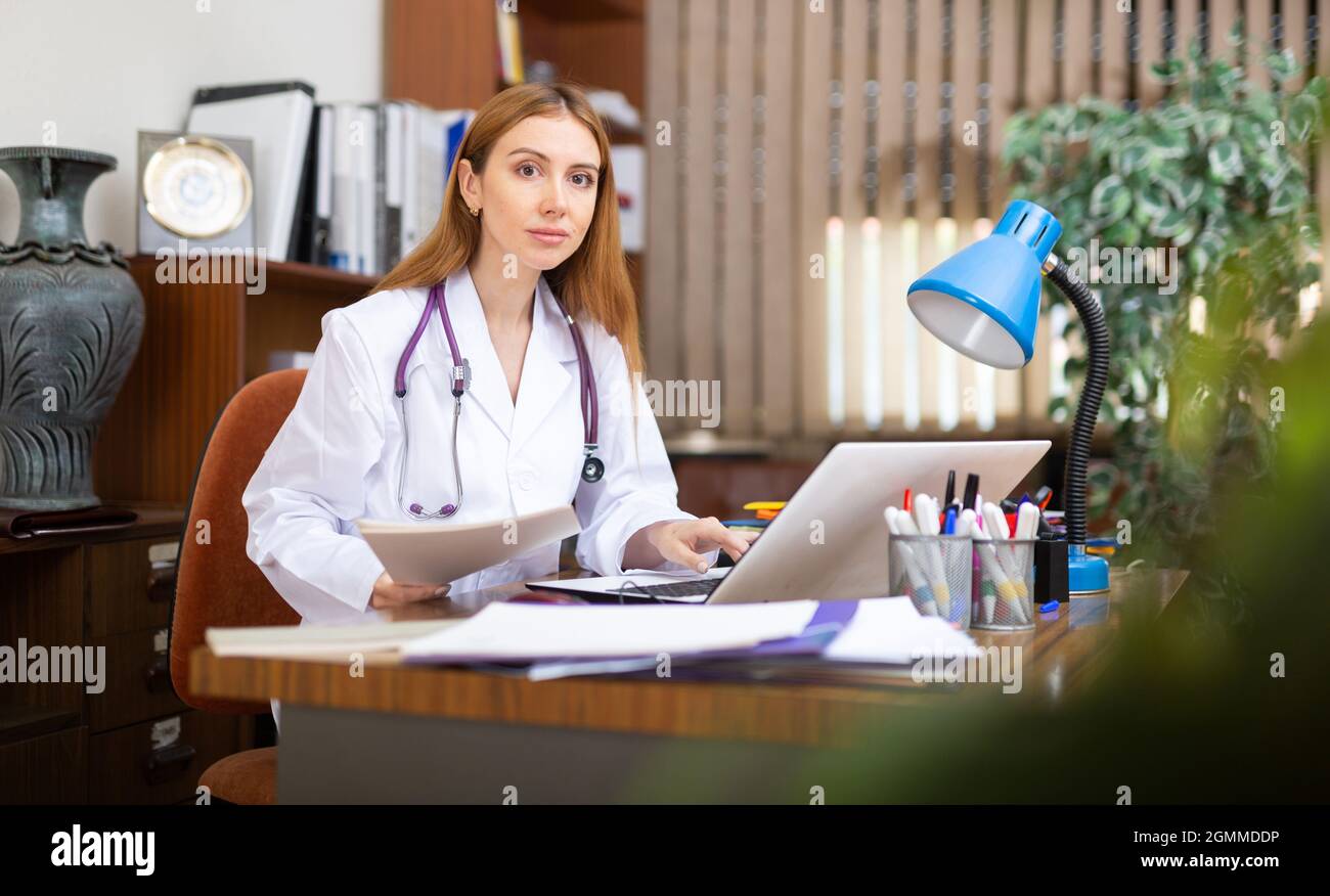 Female doctor sitting at desk in office Stock Photo - Alamy