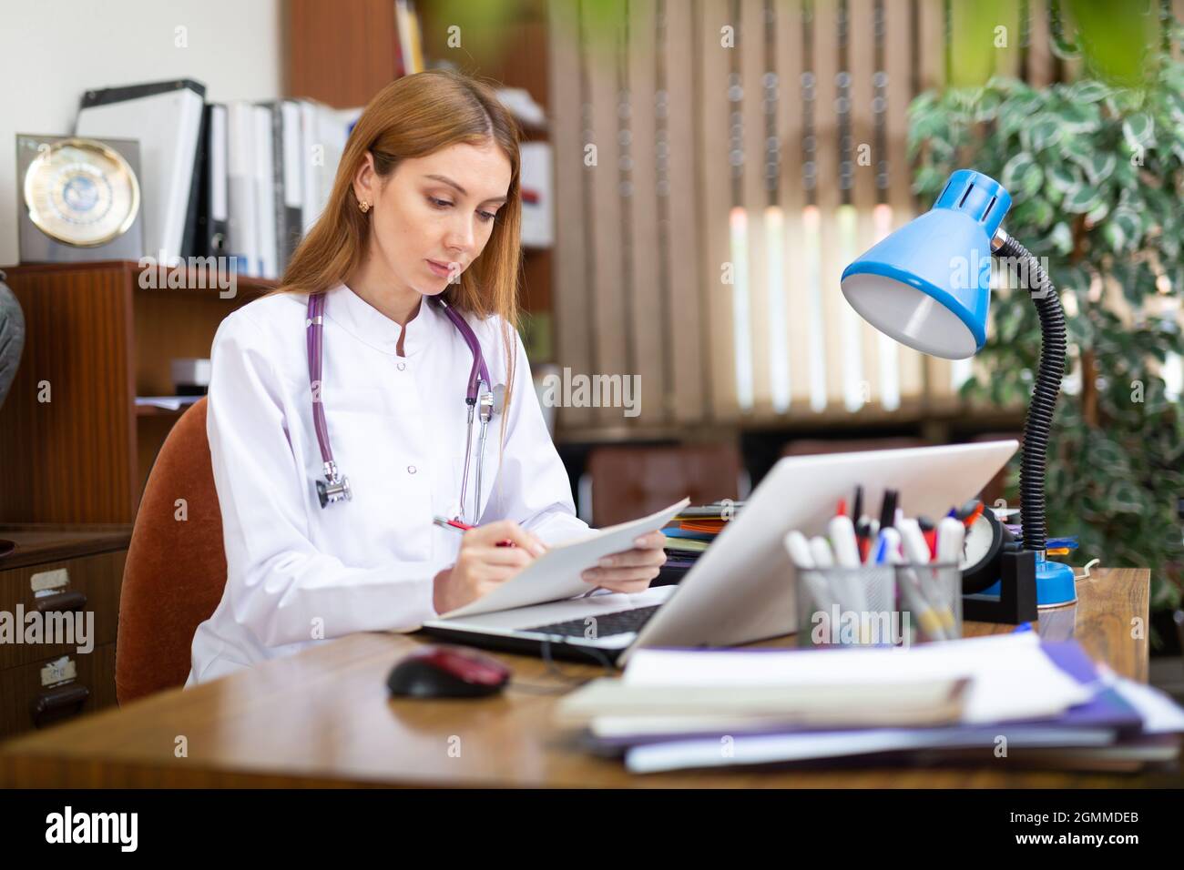 Female doctor sitting at desk in office Stock Photo - Alamy
