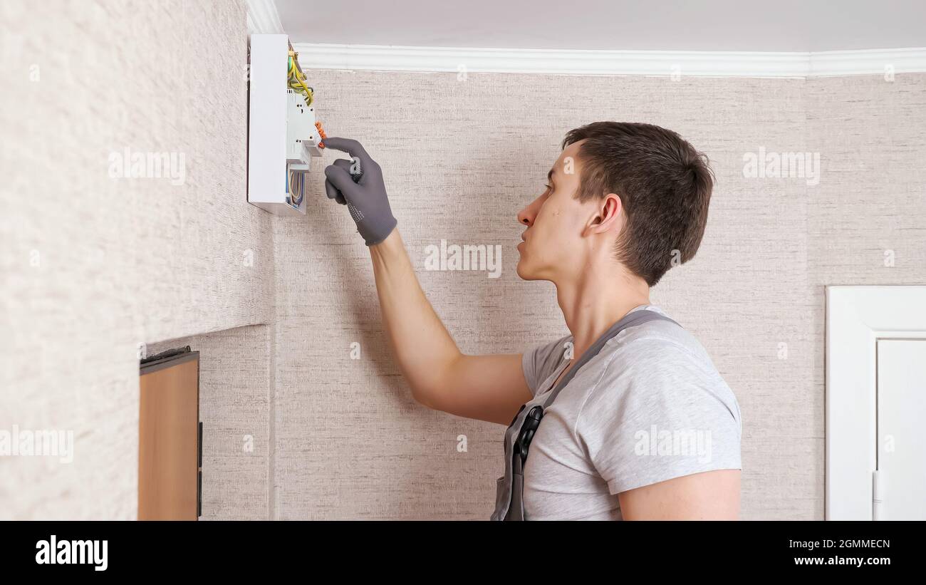 Electrician presses levers on switchboard to fix in room Stock Photo ...