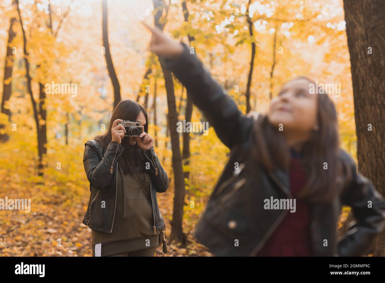Child girl photographer takes pictures of a mother in the park in ...