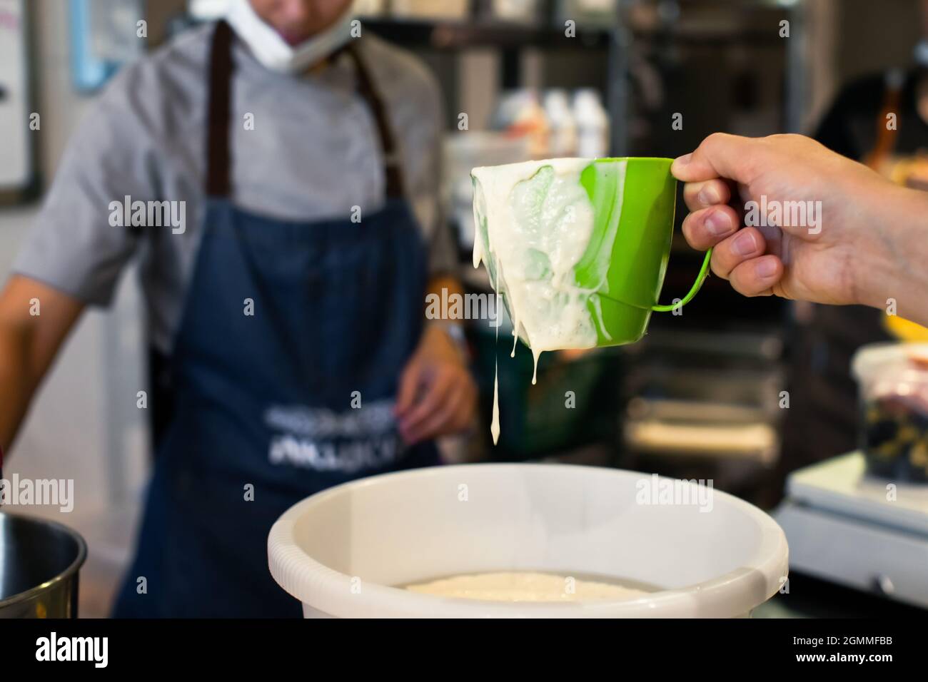 Baker measures sourdough for bread with a mug Stock Photo - Alamy