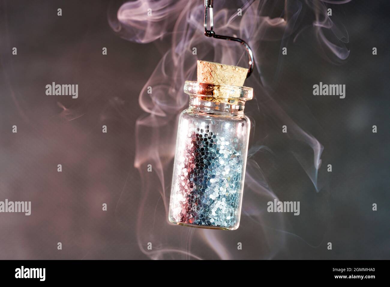 Closeup shot of glitters inside a glass vial with cork cover and smoke ...