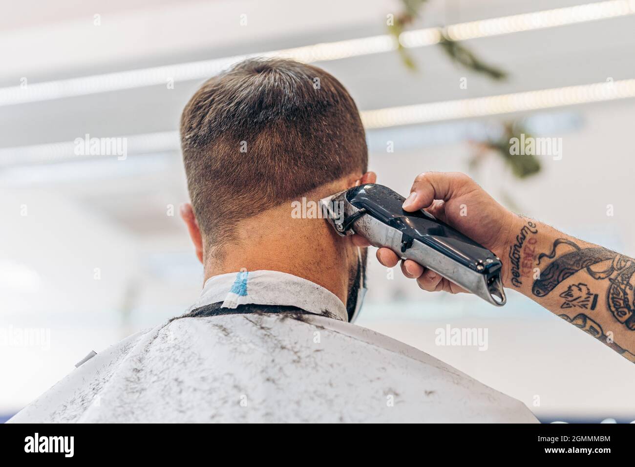Hand of a barber cutting the hair of a man using an electric machine ...