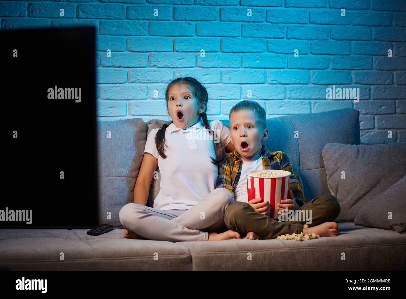 two children with remote control watching TV Stock Photo - Alamy