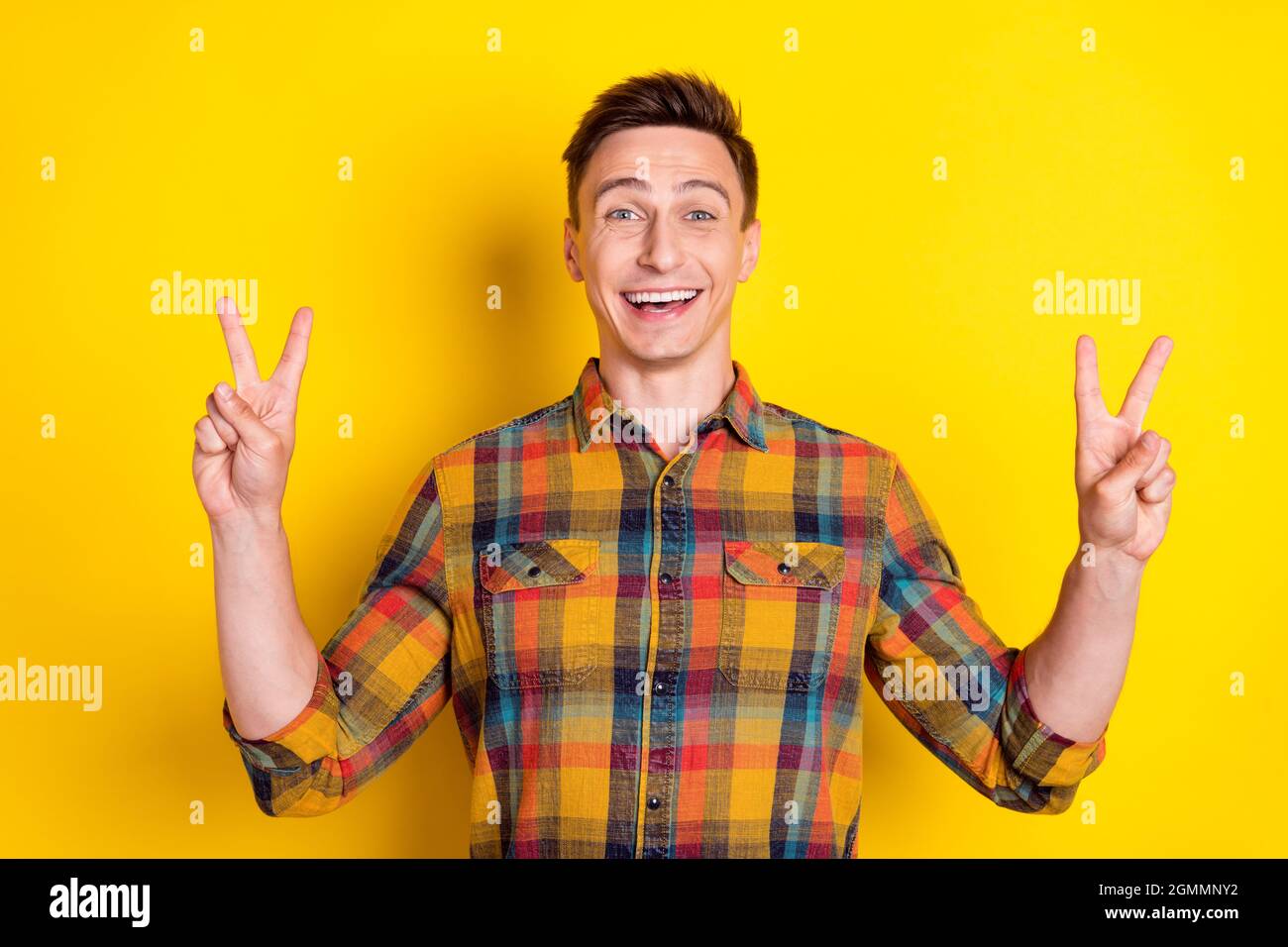 Portrait of attractive cheerful guy showing double v-sign having fun ...