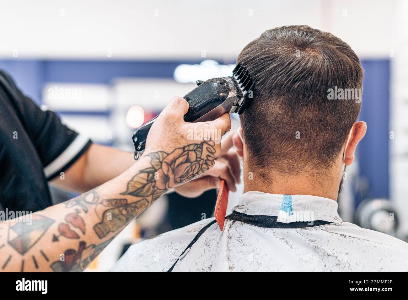 Barber cutting the hair of a man using an electric machine Stock Photo ...