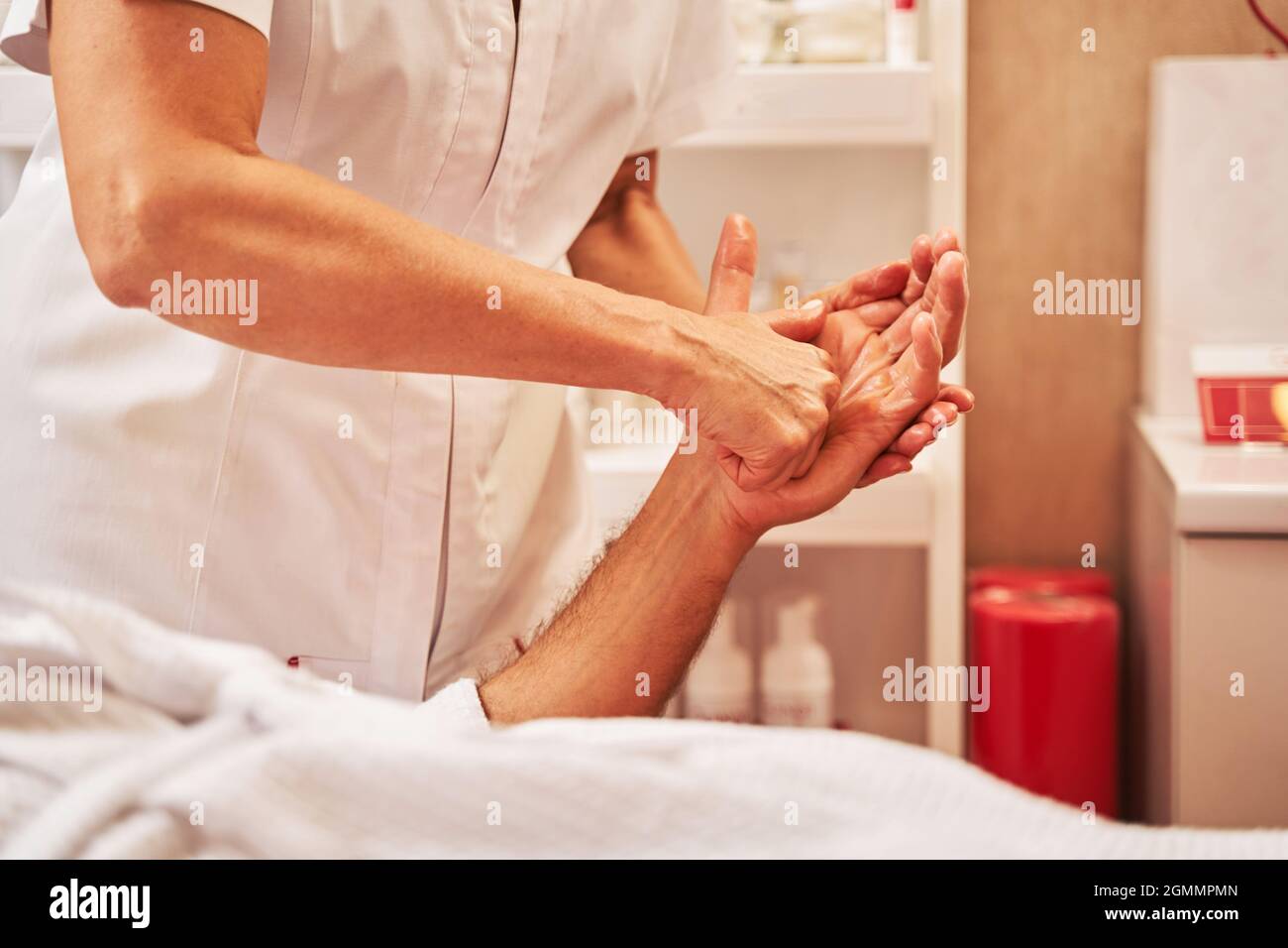 Massage therapist pressing fist into client palm Stock Photo - Alamy
