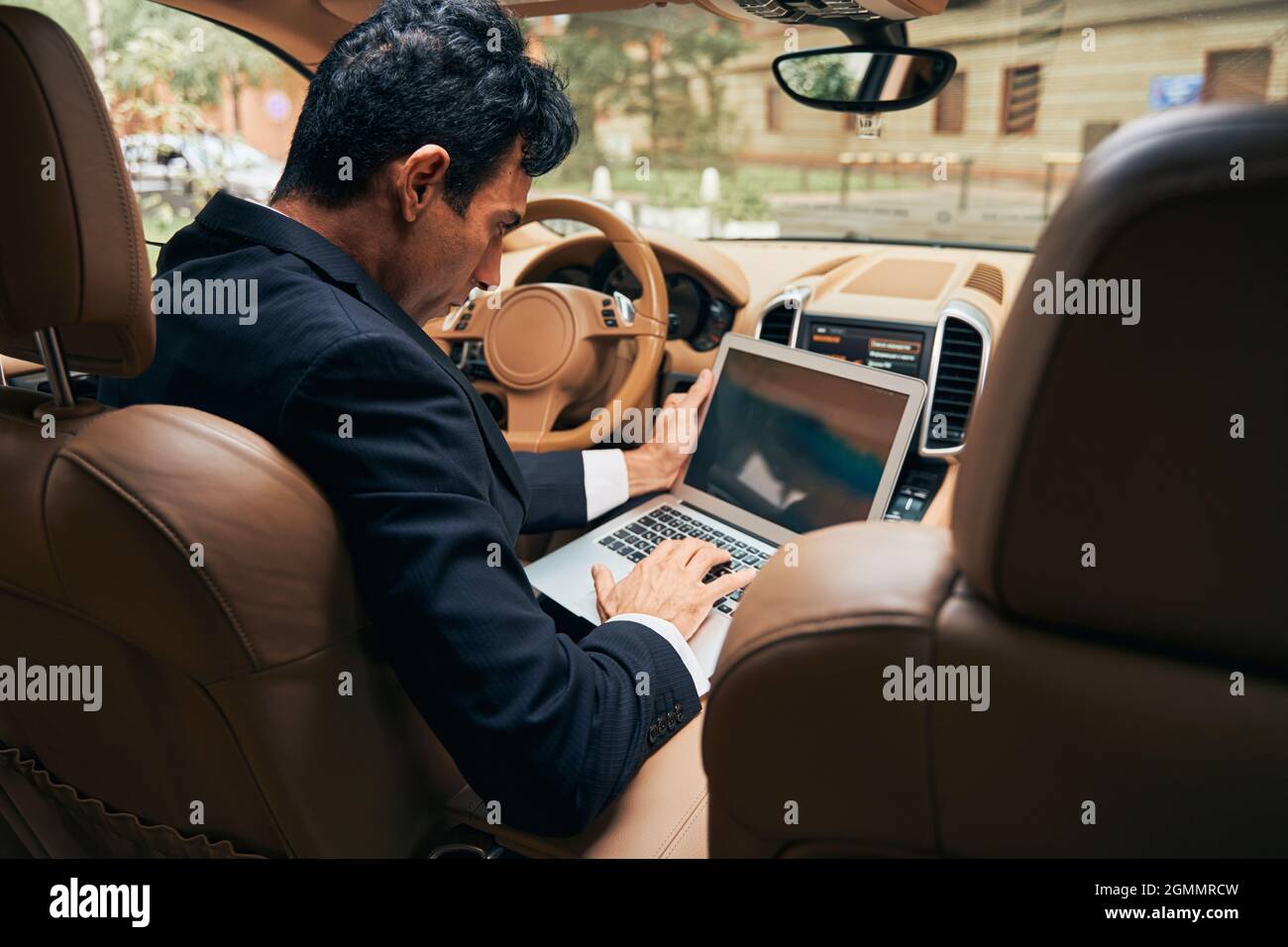 Stylish businessman working on laptop inside a car Stock Photo - Alamy