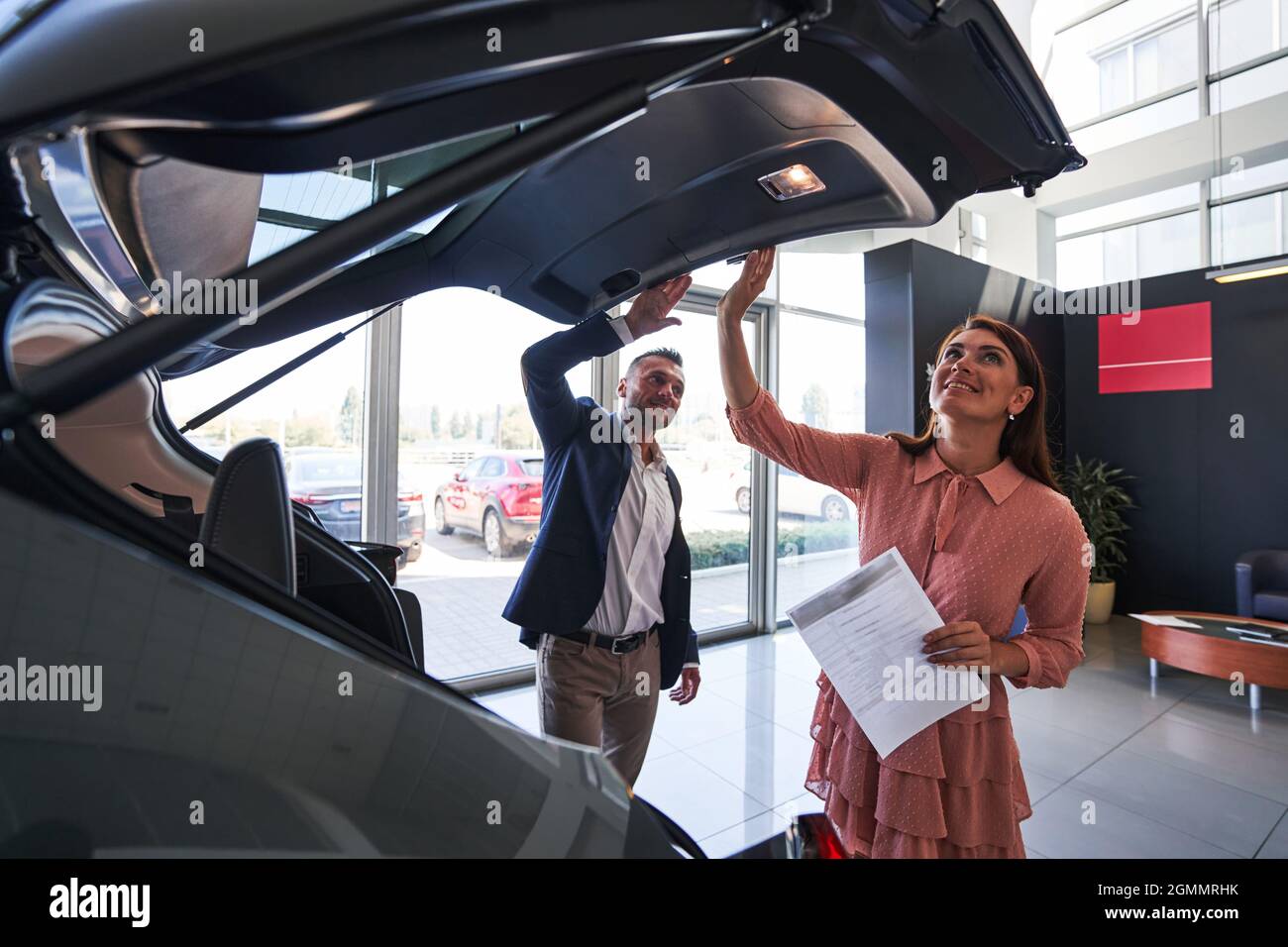 Two cheerful people opening the car in modern showroom Stock Photo - Alamy