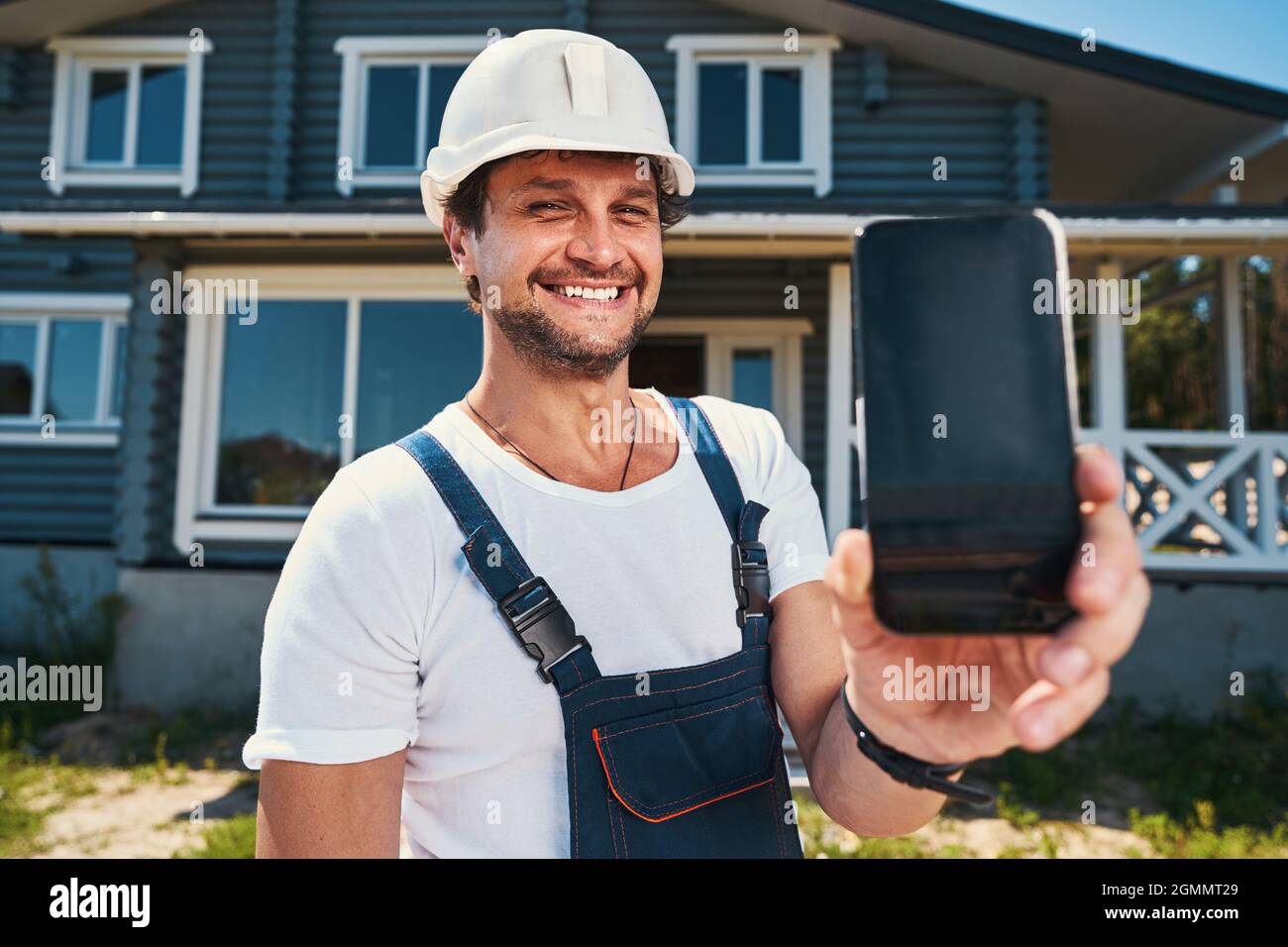 Proud housebuilder showing phone cover in hand Stock Photo - Alamy