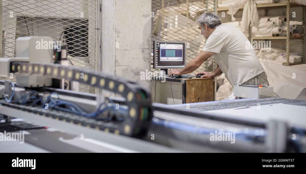 Factory worker technician works on large CNC digital cutter machine for ...