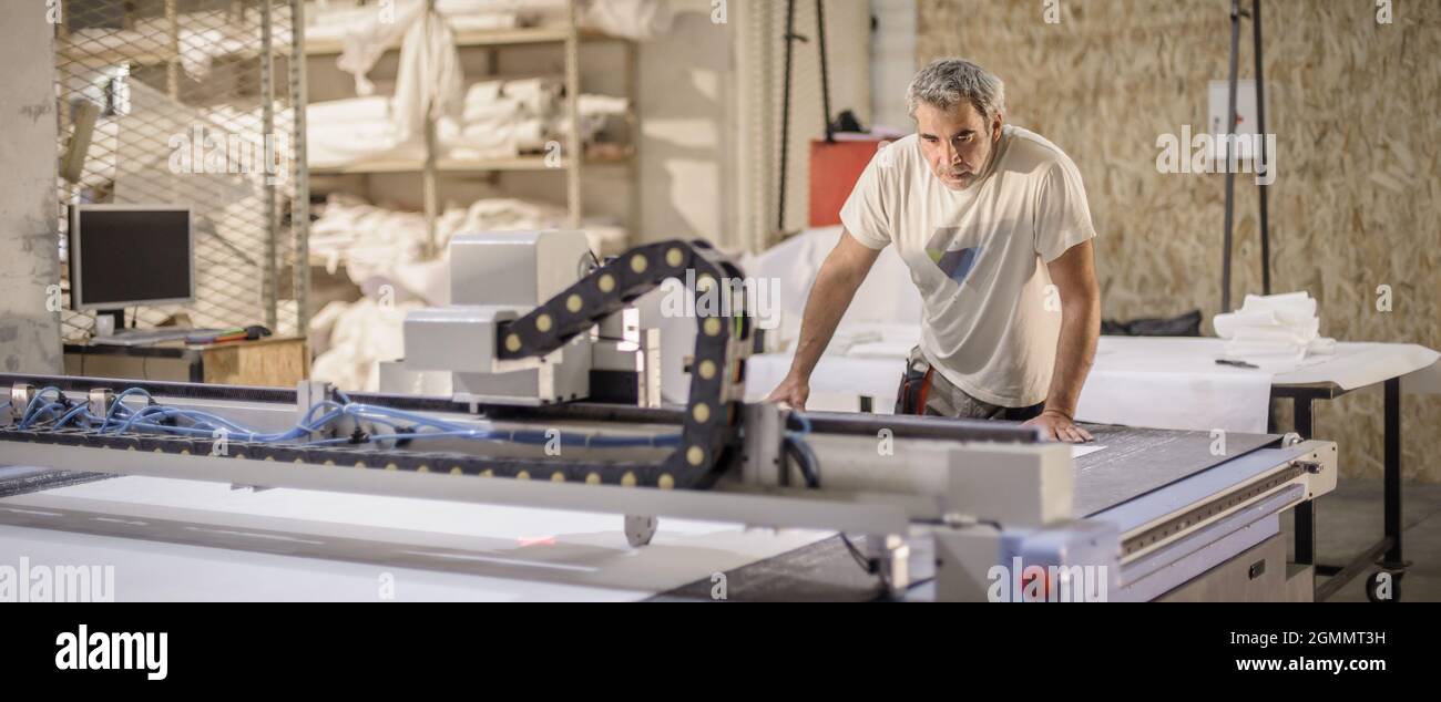 Factory worker technician works on large CNC digital cutter machine for ...