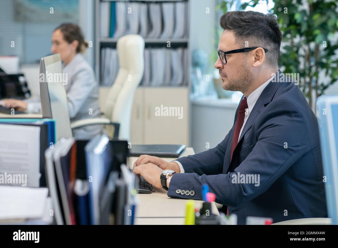 Serious businessman working in front of computer monitor against his ...