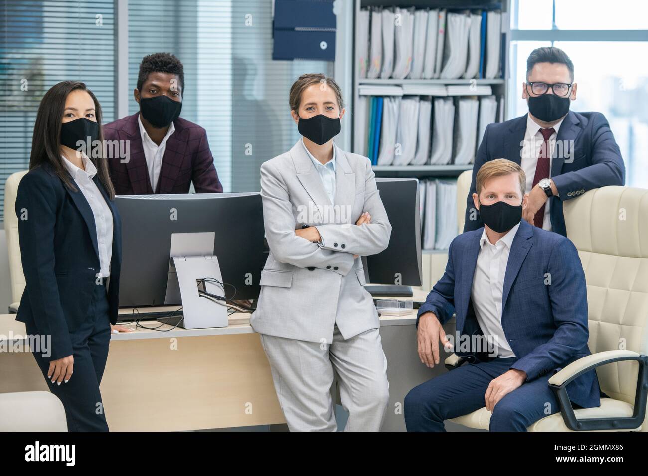 Five intercultural office managers in formalwear and black protective ...