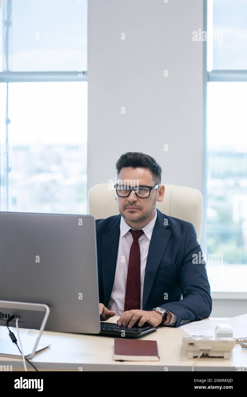 Busy man in formalwear typing on computer keyboard while sitting by ...