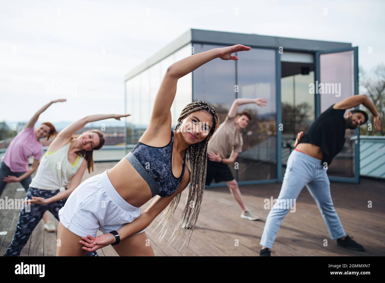 Group of young people doing exercise outdoors on terrace, sport and ...