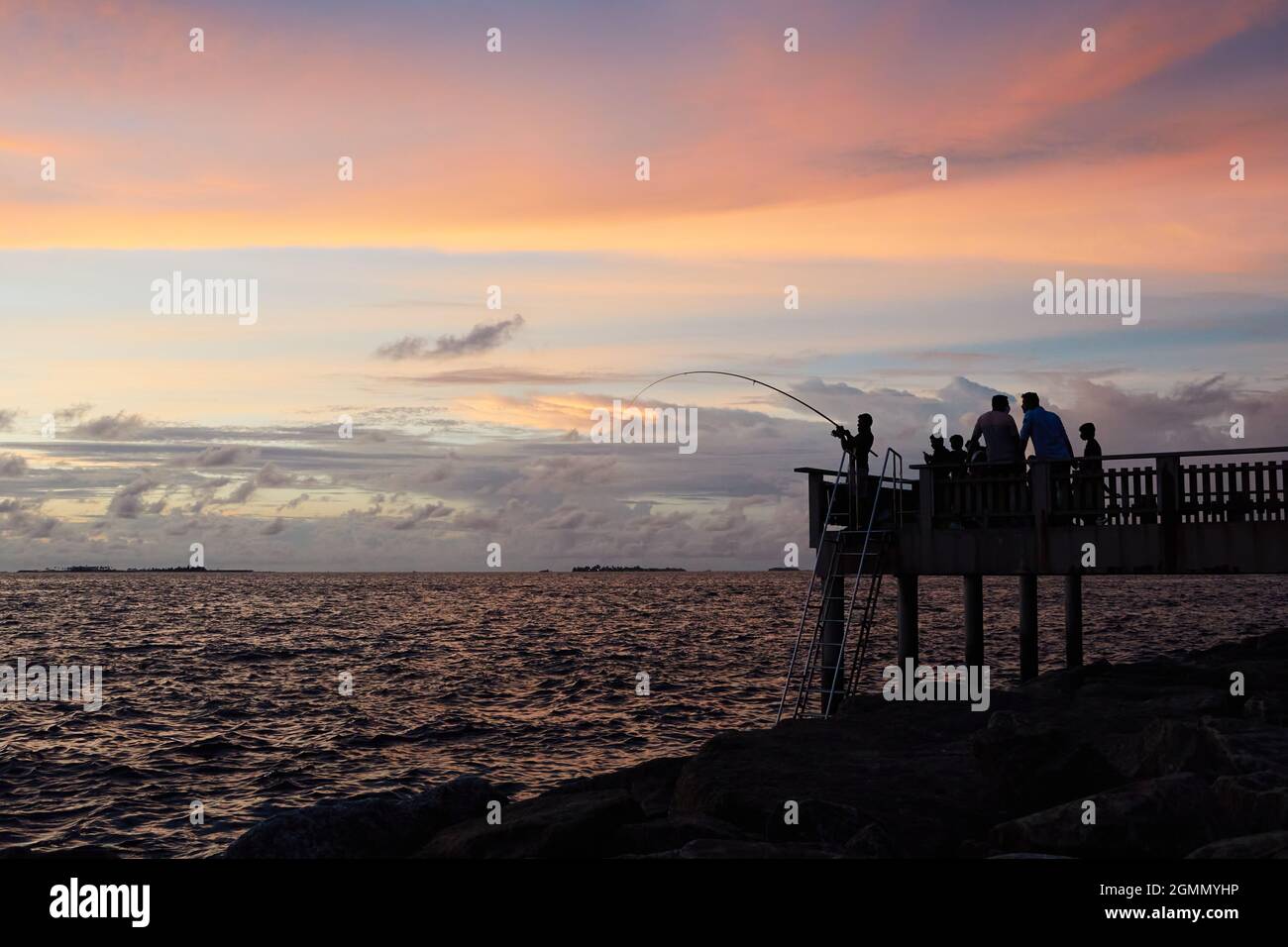 Fisherman hooked a fish at dusk Stock Photo - Alamy