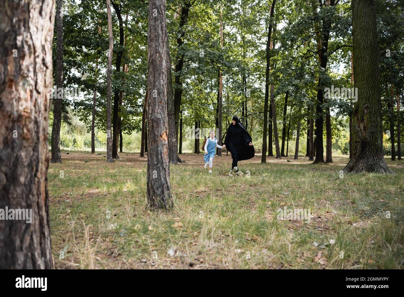 Smiling mother and muslim daughter running in park Stock Photo - Alamy